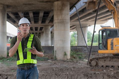 기술자는 배경에 백 호와 함께 건설 현장에서 일하고 있습니다 30 34세에 대한 스톡 사진 및 기타 이미지 30 34세 개발 건설 기계류 Istock