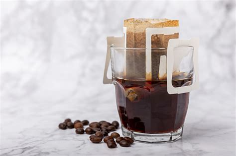 커피 백 커피 원두 유리 컵을 텍스처 테이블에 떨어 뜨립니다 컵에 양조하기 위한 분쇄 커피 종이 봉지 드립 커피 필터 포장