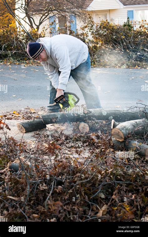 Man Cutting Tree Limbs With A Chainsaw That Have Fallen From Storm Damage A Late Fall Snow