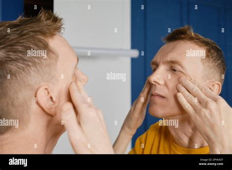 Concentrated Man Massaging And Rubbing Lotion Under His Eyes Stock Photo Alamy