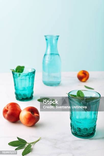아름다운 빈티지 청록색 안경 2개 차가운 음료와 얼음 조각이 담긴 병 흰색 대리석 테이블에 신선한 녹색 민트 잎으로 장식된 과일 0명에 대한 스톡 사진 및 기타 이미지
