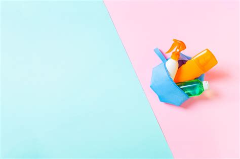 선크림 스프레이 선스린 선스린 바디 로션 Spf 크림이 가득한 여성 화장품 가방의 탑 뷰를 복사 공간이 있는 파란색과 분홍색 배경에 얹어 보냅니다 바로 위의 밝은 여름 컨셉
