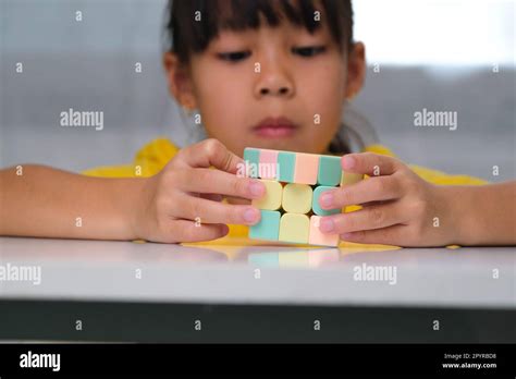 asian little cute girl holding rubik s cube in her hands and playing with it rubik s cube is a