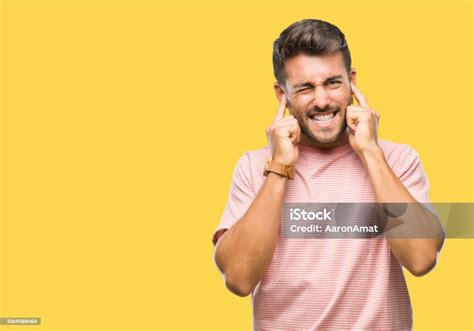 시끄러운 음악의 소음에 대 한 짜증이 식이 손가락으로 귀를 덮고 격리 된 배경 위에 젊은 잘생긴 남자 청각 장애인 개념입니다 가리기에 대한 스톡 사진 및 기타 이미지