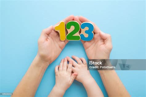 밝은 파란색 테이블 배경에 아기에게 다채로운 나무 숫자를 보여주는 젊은 성인 어머니의 손 파스텔 색상 학습 할 시간입니다 관점 샷 근접 촬영 하향 보기 2명에 대한 스톡