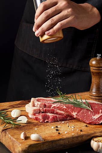 요리사는 부엌 어두운 배경 다양한 향신료 에서 신선한 스테이크를 소금에 절입니다 굽기에 대한 스톡 사진 및 기타 이미지 Istock