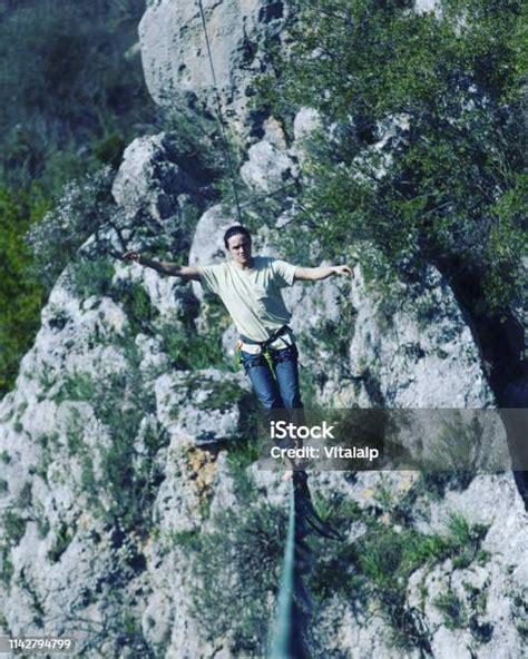 남자는 뻗어 슬링을 따라 걷고 있다 산에서 하이 라인 남자는 균형을 잡는 다 자연에서 줄 타기 워커의 성능 계곡의 배경에 높은