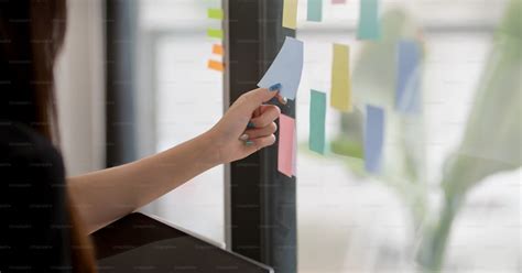 여성 콘텐츠 제작자의 측면보기는 사무실의 유리 벽에 아이디어를 상기시키기 위해 스티커 메모를 사용합니다 사진 Unsplash의 태국 이미지