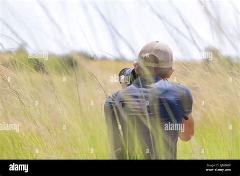 A Male Photographer Capturing Nature In A Field During Daylight Stock