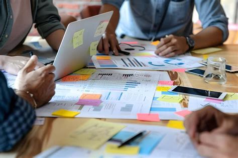 Team Collaborates On Project Analyzing Data With Charts And Sticky Notes Utilizing Laptop For