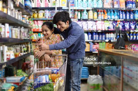 슈퍼마켓에서 식료품을 사며 행복한 인도 남자가 선반 앞에 서서 행복한 순간을 보내고 있다 손에 제품을 들고 자격 증명을 확인합니다 10 11세에 대한 스톡 사진 및 기타