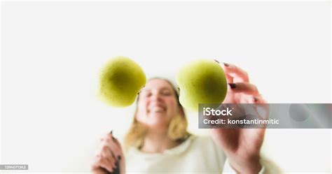 하얀 드레스를 입은 금발 여성의 유리를 통해 낮은 각도에서 녹색 사과를 커팅 보드에서 반으로 자르는 장면 건강한 식습관의 개념