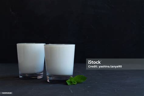 검은 색 배경에 우유 유리 신선한 녹색 민트와 블랙에 Lassi 음료 차가운 유제품 인도 요리 복사 공간을 복사합니다 아이란 흰색 테이블에 프로바이오틱스와 요구르트 건강하고