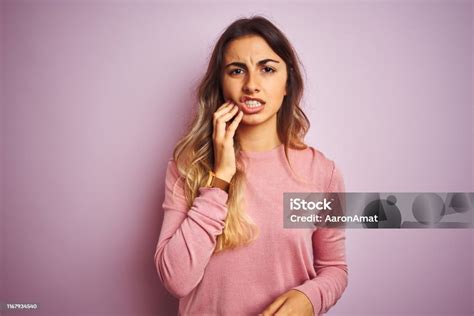 분홍색 고립 된 배경 위에 스웨터를 입은 젊은 아름다운 여성은 치아에 치통이나 치과 질환으로 인해 고통스러운 표정으로 입을 만지고 있습니다 치과 의사 개념 사람 이빨에 대한