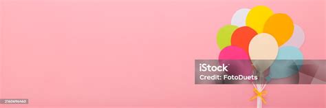 밝은 분홍색 테이블 배경에 흰색 문자열과 리본이 있는 응용 프로그램 종이에서 다채로운 풍선 모양의 무리 파스텔 색상 근접 촬영 와이드 배너 텍스트를 위한 빈 공간입니다