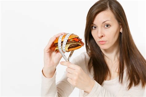 여자를 가까이 손 주위에 테이프를 측정 하는 재단사와 함께 햄버거 흰색 배경에 고립에서 보유 합니다 적절 한 영양 섭취 또는 고전적인 미국의 패스트 푸드입니다 광고에 대 한