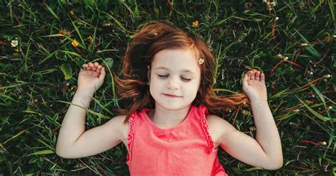 초원의 풀밭에서 쉬고 있는 꿈을 꾸는 귀여운 백인 소녀 아이는 땅에 누워 자고 있습니다 야외 활동 재미 여름 어린이 활동 행복한 어린 시절 생활 방식 위에서 본 모습