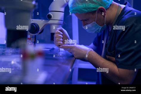 Laboratory Worker Examining Fluid Under Microscope In Clinic Stock