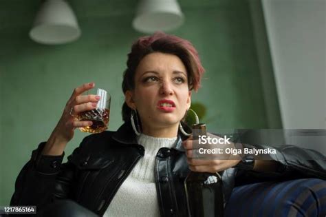 글램 록 스타일의 모습을 가진 어두운 분홍색 머리를 가진 젊은 슬픈 여성은 얼굴에 가증한 찡그린 얼굴 여성 알코올 중독 알코올