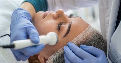 미용사로부터 각질 제거 회춘 및 수분 공급으로 전문적인 절차를 받는 젊은 여성 얼굴 피부 초음파 캐비테이션 사진