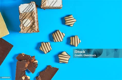 초콜릿 바와 사탕 근처 슬라이스 체크 무늬 직사각형 케이크는 파티의 파란색 테이블에 놓여있습니다 축 하 개념입니다 텍스트의 공백입니다 맨 위 보기 공휴일에 대한 스톡 사진