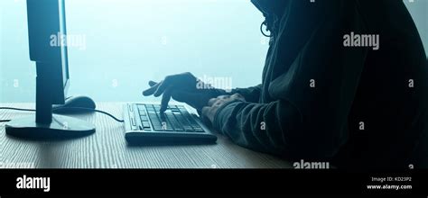 hooded computer hacker hacking network male with black hoodie using