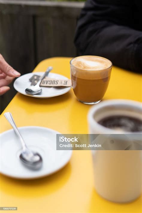 커피 한 잔마시고 있는 두 사람 하나는 우유가없는 아메리카노를 마시고 다른 하나는 라떼를 마시고 있습니다 밝은 노란색 테이블에