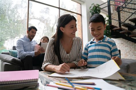 엄마와 아들이 노트북에 숙제를 하는 동안 아빠와 딸이 배경에서 태블릿으로 플레이 합니다 10 11세에 대한 스톡 사진 및 기타 이미지 10 11세 12 13세 30
