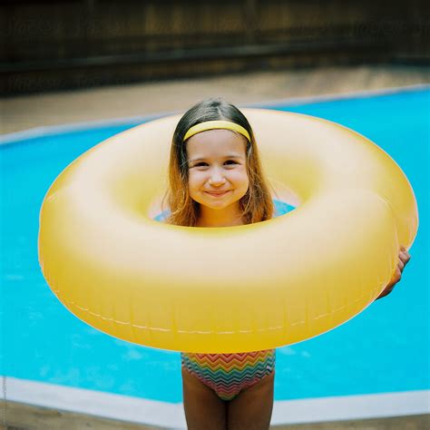 Cute Young Girl With A Big Inter Tube Standing By A Swimming Pool By Stocksy Contributor