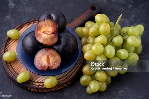 잘 익은 유기농 검은 자두 반으로 잘라 육즙 펄프와 어두운 돌 배경에 흰색 포도의 무리 옆에 도마에 비건 메뉴 건강한 식사 가을에 대한 스톡 사진 및 기타 이미지 Istock