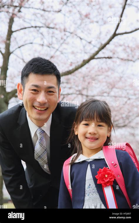 Japanese Father And Daughter With Cherry Blossoms In A City Park Stock