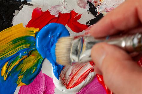 아티스트 팔레트에서 파란색을 따기 페인트 브러시로 인간의 손을 닫습니다 예술가 스튜디오 또는 창조적 인 교육을 보여주는 학교에서 다채로운 이미지 선택적 초점 공예에 대한