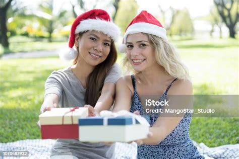산타 모자를 착용 하 고 선물 상자를 주는 행복 한 예쁜 여자 2명에 대한 스톡 사진 및 기타 이미지 2명 개념 공원