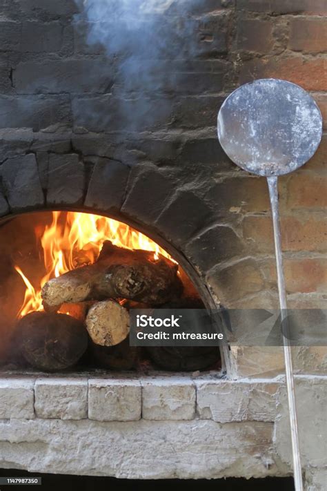 전통적인 야외 벽돌 피자 오븐의 마법사 나무 불타는 난로 나무와 토지 처리의 레코딩 로그와 이탈리아 레스토랑 피자 금속 피자 외륜 삽 꺼져 가는 불에 대한 스톡 사진 및