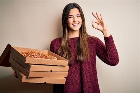 손가락으로 확인 기호를하고 흰색 배경 위에 서 이탈리아 피자와 배달 상자를 들고 젊은 아름다운 소녀 우수한 기호 개념에 대한 스톡 사진 및 기타 이미지 Istock