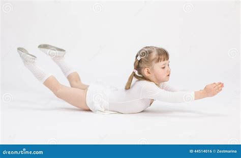 Милая маленькая девочка лежа на поле и делая тренировку Стоковое Фото изображение