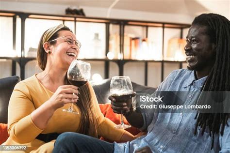 소파에 앉아있는 와인 잔을 깜박이는 다문화 가장 친한 친구 거실에서 함께 즐겁게 교류하는 2 명 2명에 대한 스톡 사진 및 기타 이미지 Istock