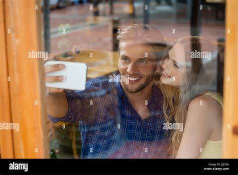 Happy Couple Clicking Selfie With Smart Phone While Sitting At Cafe