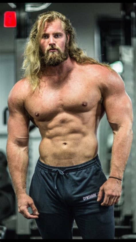 A Man With Long Hair And No Shirt Standing In Front Of A Gym Equipment Area