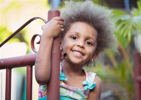 A Young Girl With Frizzy Brown Hair Smiling Happily By Stocksy