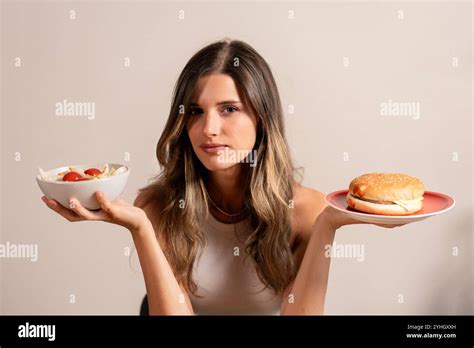 Young Woman Holding Healthy Salad And Hamburger Showing Food Choice