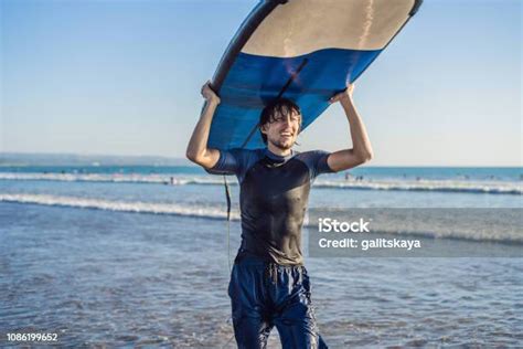 남자는 그의 머리 위로 서핑 보드를 들고입니다 해변에서 머리에 서핑 보드와 잘생긴 남자 닫습니다 Hid 헤드에 서핑 보드를 들고 해변에서 웃 고 남자의 초상화 균형에 대한