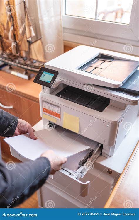 Woman Putting Paper In A Printer To Make Photocopies And Teleworking From Home Stock Image