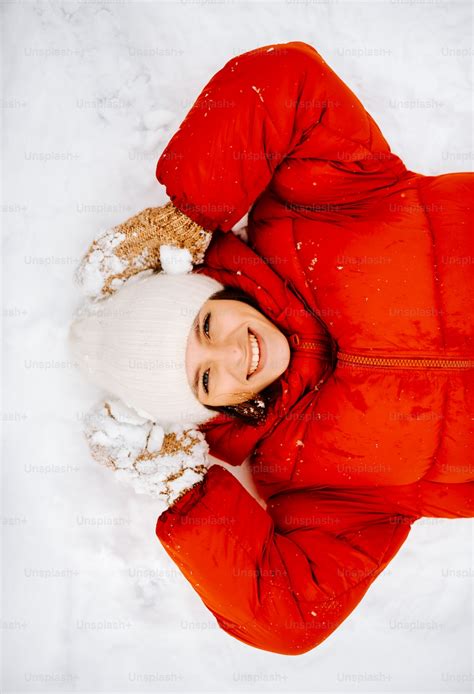 빨간 재킷을 입은 여자가 눈 속에 누워 있다 사진 Unsplash의 코트 이미지