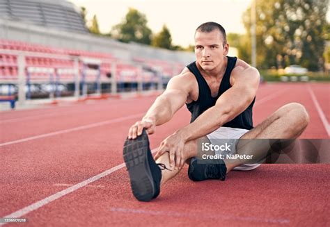 조깅과 유연성 개념 젊은 근육 운동 주자 남자가 달리기 시작하기 전에 앉아있는 자세로 달리기 코트에서 발을 뻗고 만지는 것은 주자의 얼굴에 집중합니다 20 24세에 대한