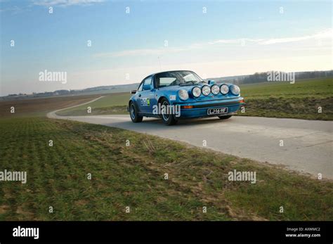 Blue Porsche 911 Carrera At Speed On Tarmac Country Road International