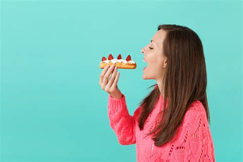 젊은 여자의 모습 짠 핑크 스웨터 닫힌된 눈 보류와 손잡고 청색 청록색 배경 스튜디오 초상화에 절연 클 레어과 자를 케이크를 먹는 사람들의 라이프 스타일 개념입니다 복사