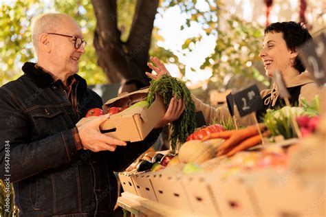 Cheerful Woman Giving Box Full Of Fresh Fruits And Veggies To Elderly Customer Working At Local