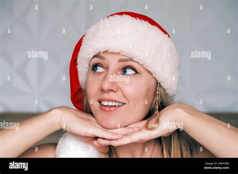 Smiling Santa Girl Wearing Red Hat Is Laying Her Chin On Both Hands Looking Up Side Portrait Of