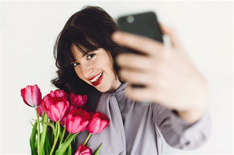 Selfie 튤립의 선물 상자 흰색 배경 실내 공간 텍스트에 대 한 부케와 복용 아름 다운 행복 한 소녀 꽃과 전화 세련 된 젊은 여자 국제 여성의 날 감정에 대한 스톡
